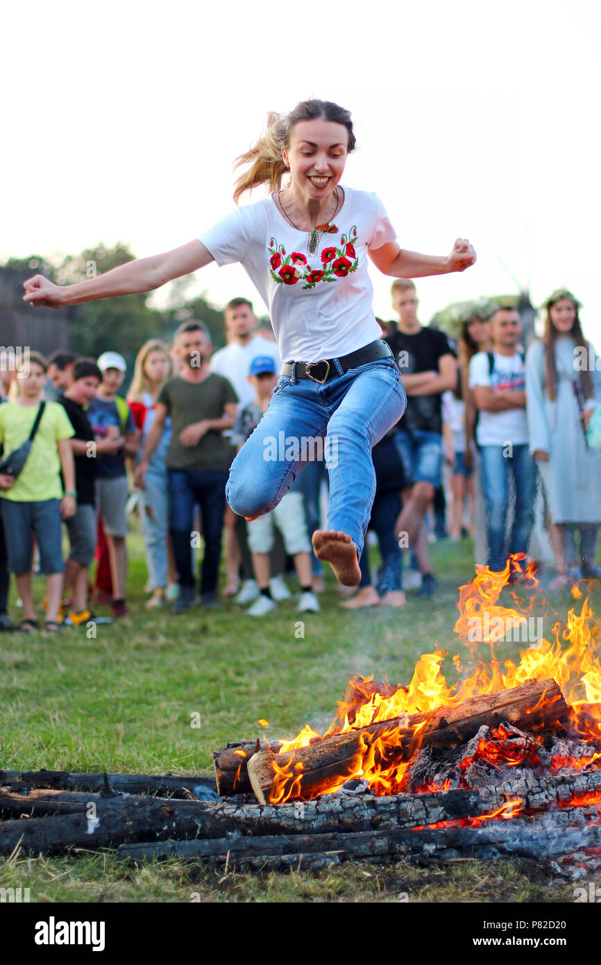 KYIV, UKRAINE - JULY 6, 2018: Young people jump over the flames of ...