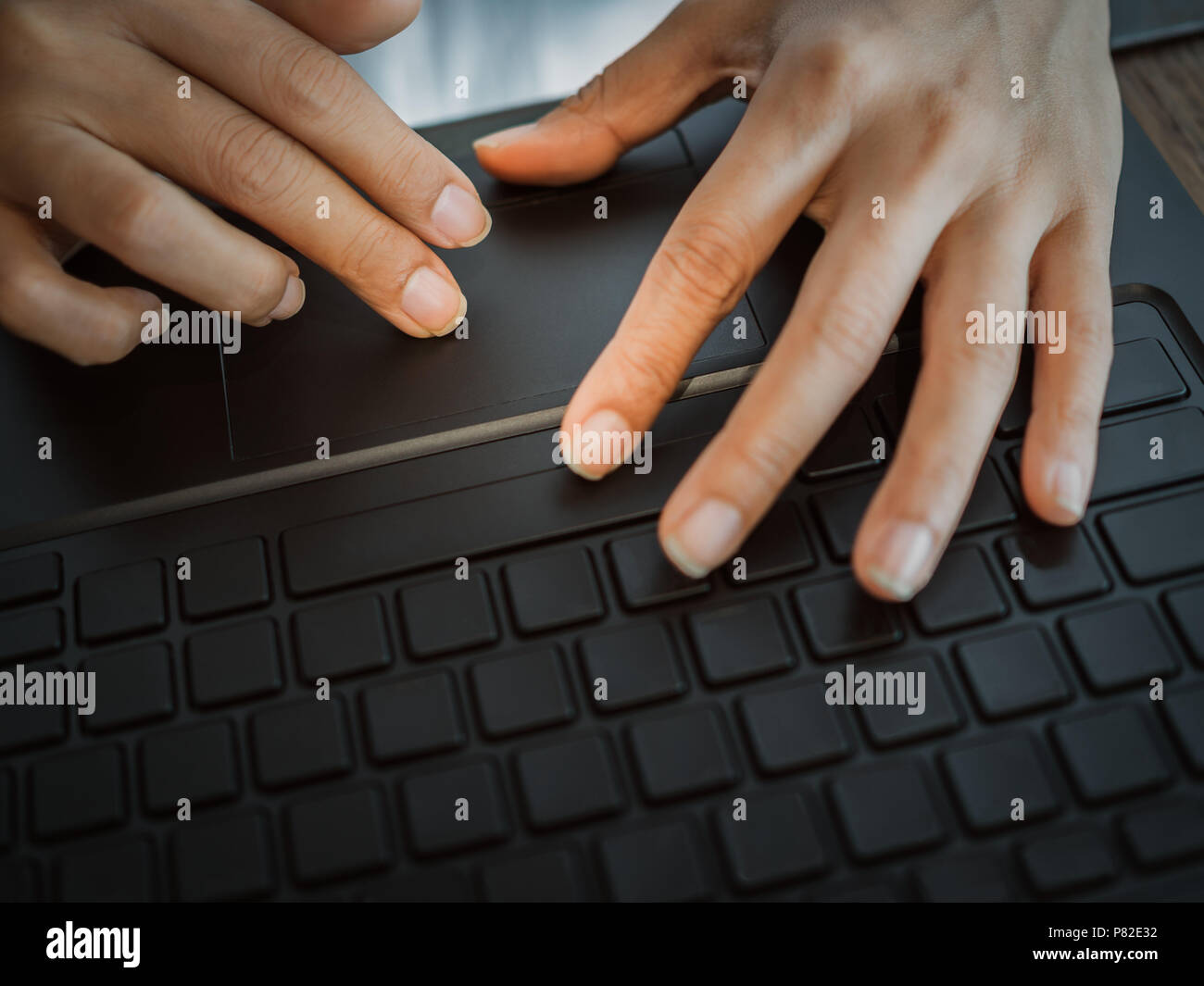 Close-up hands touching pad on computer laptop keyboard on wooden table ...
