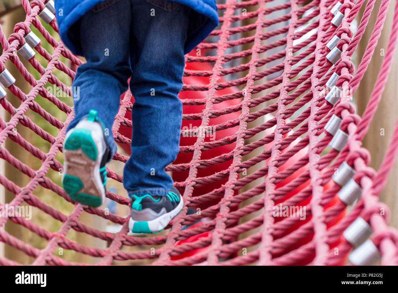 Young child playing on a rope climbing frame in Battersea Park, London ...