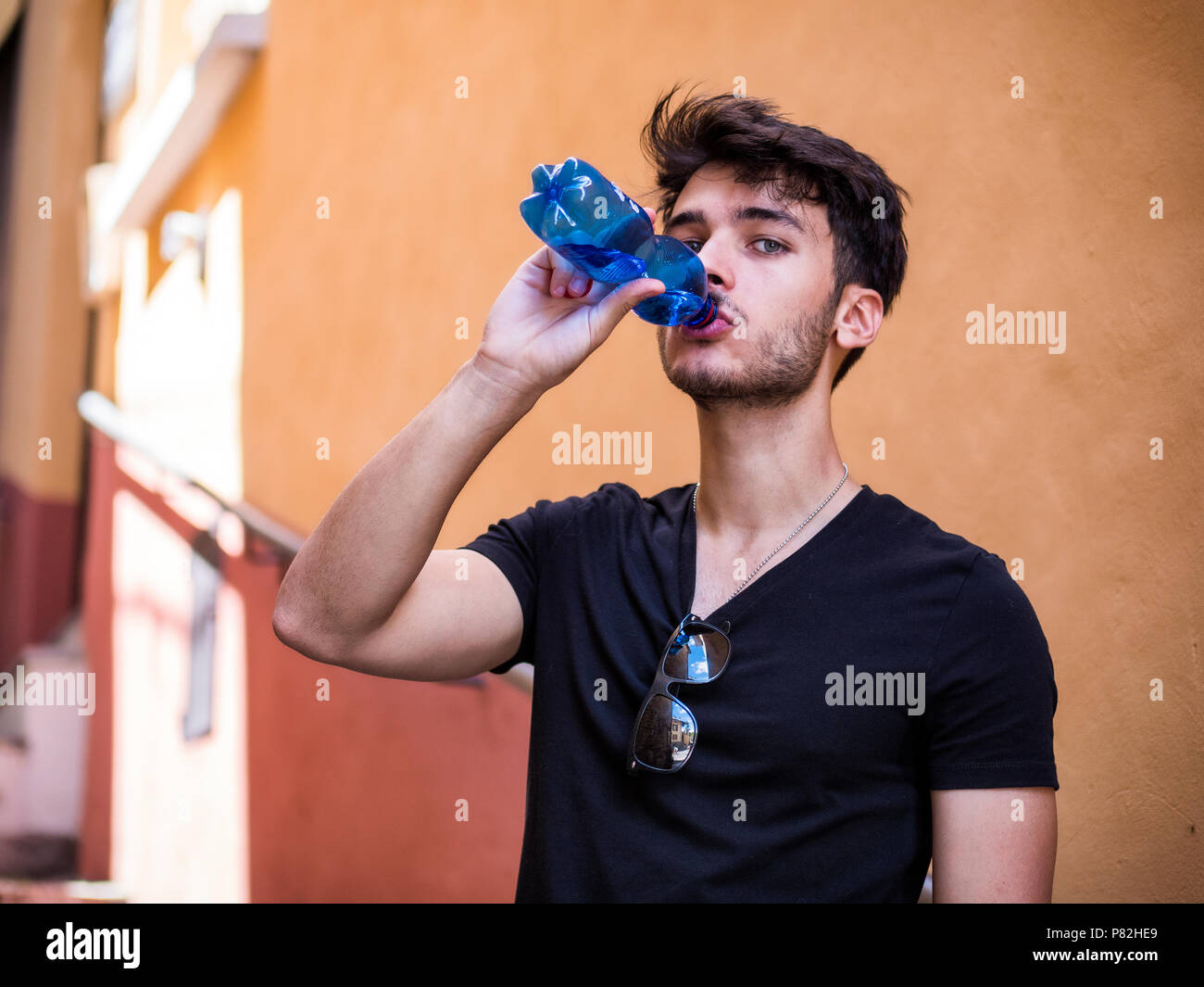 Handsome young man drinking water from bottle Stock Photo - Alamy
