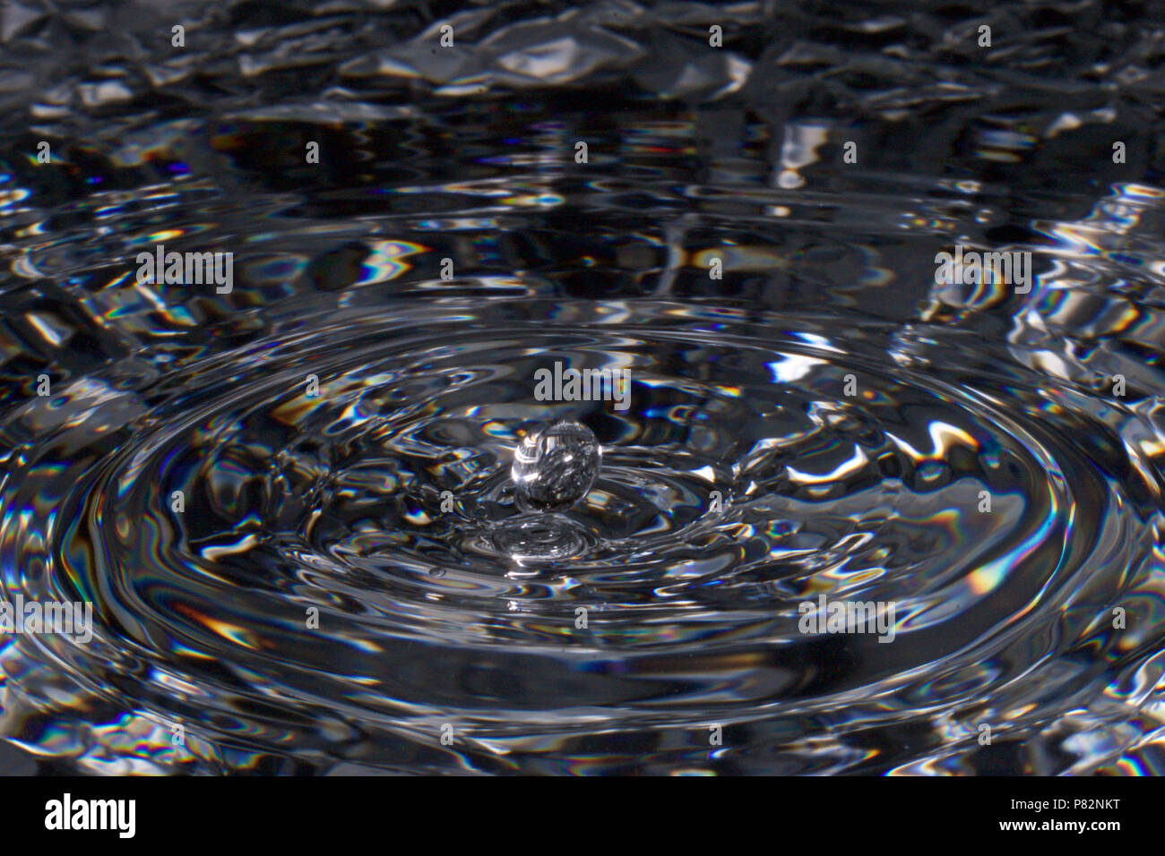 Water droplets falling into water causing splashes and ripples Stock ...