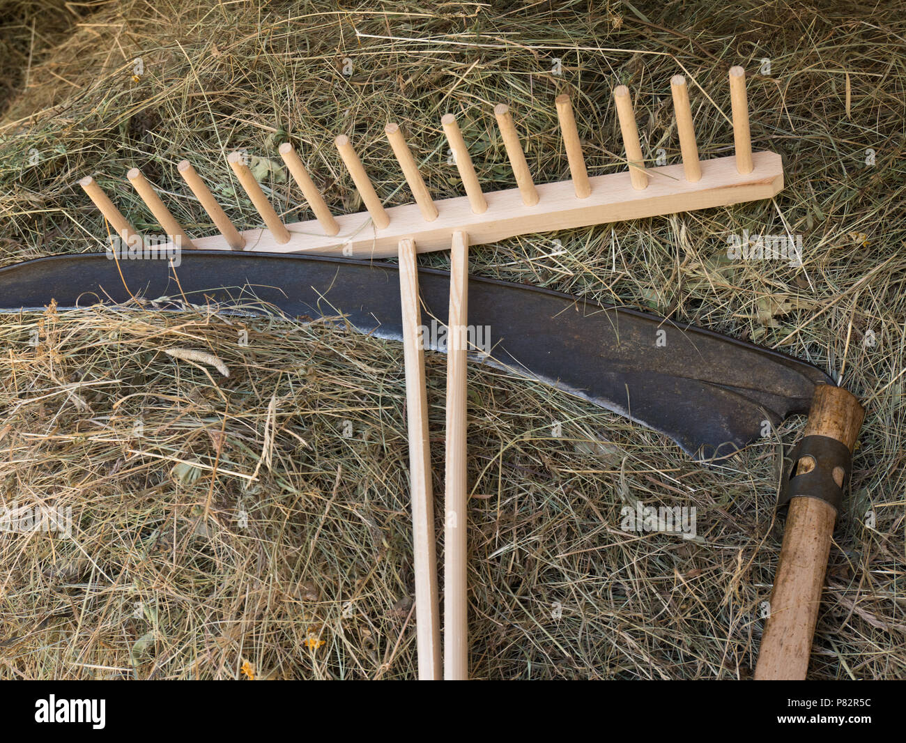 A scythe and a rake with hay Stock Photo - Alamy