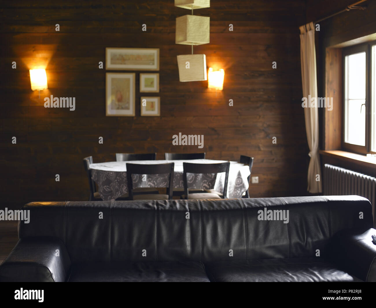 Round dining table and a leather sofa in a cozy living room, focus in ...