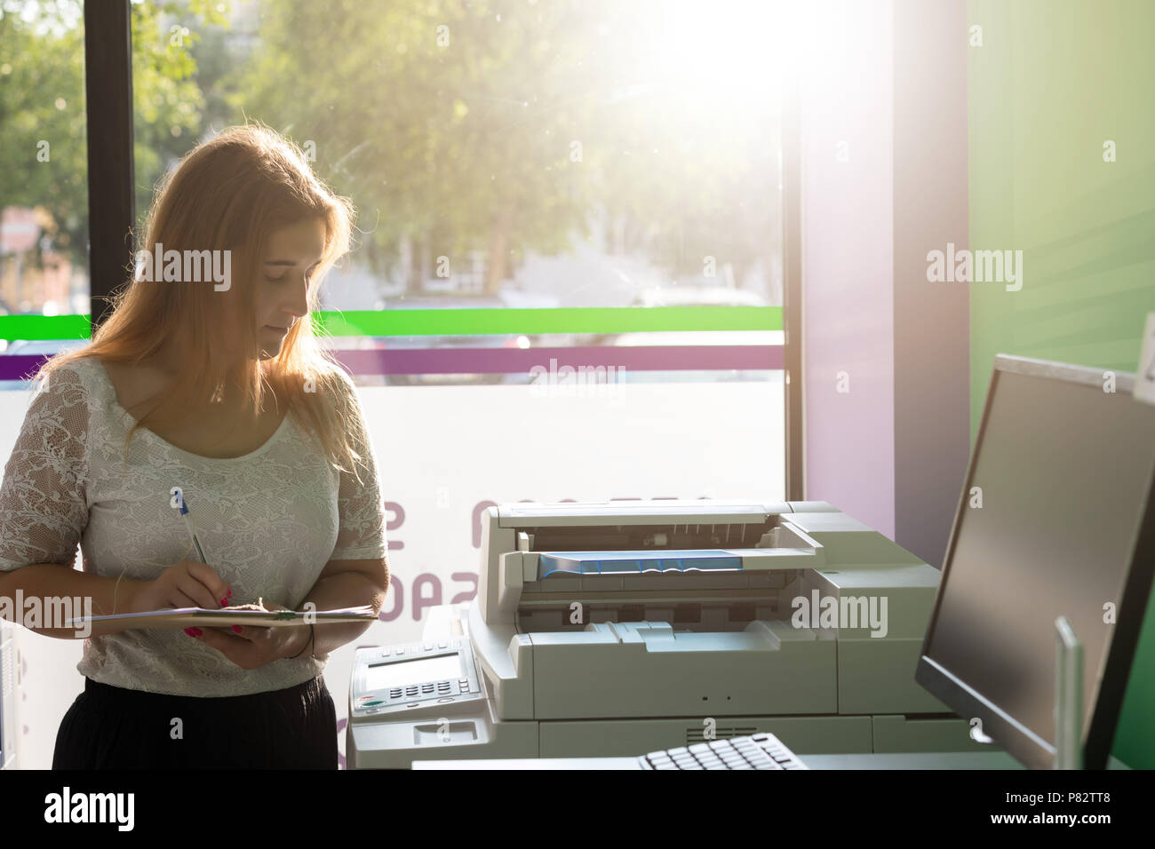 A young student at a copy center taking some copies for her final exams ...