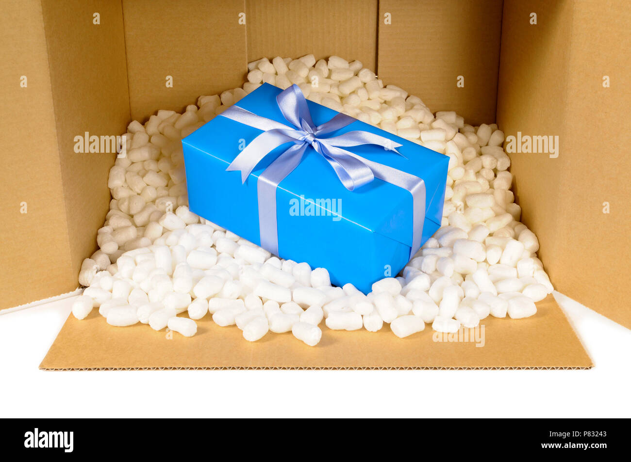 Cardboard shipping delivery box with blue gift inside and polystyrene ...