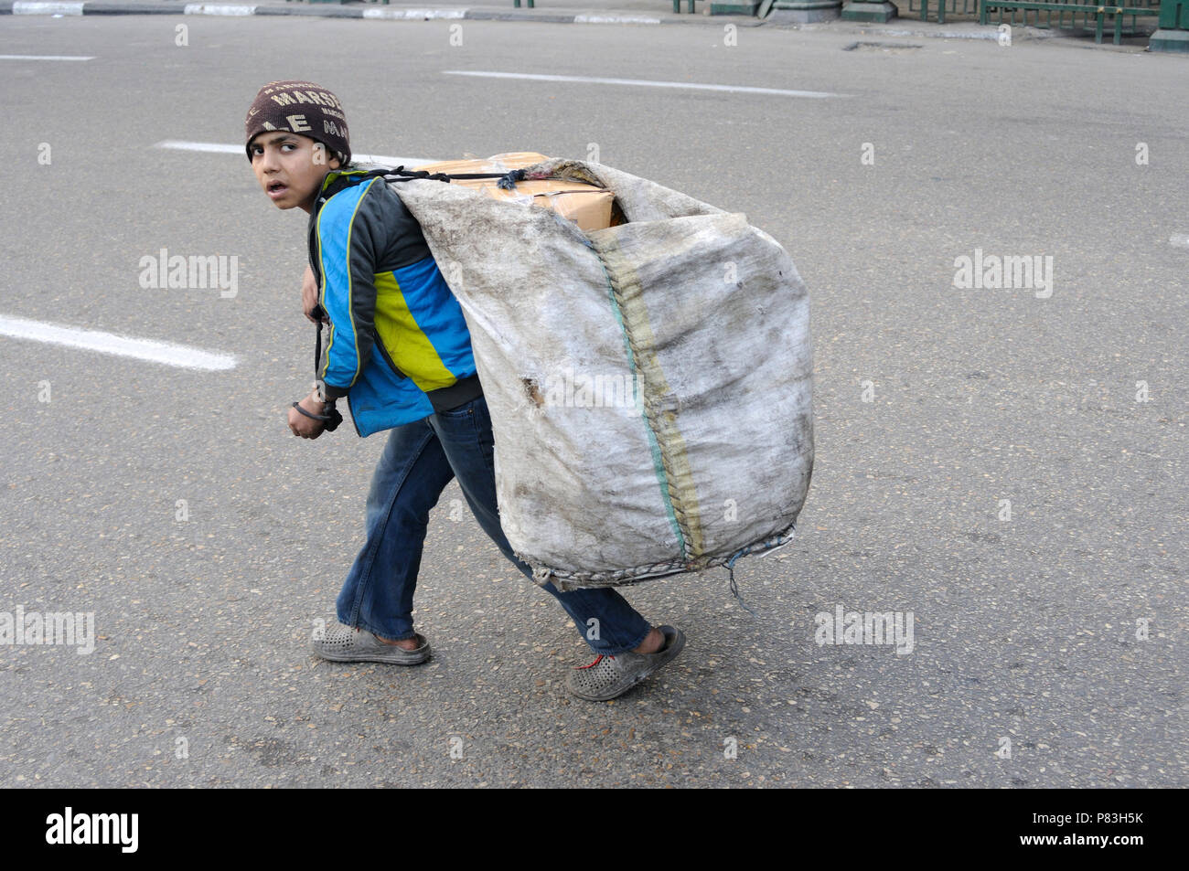 A little boy drags a garbage bag on his back in Cairo-Downtown, taken ...