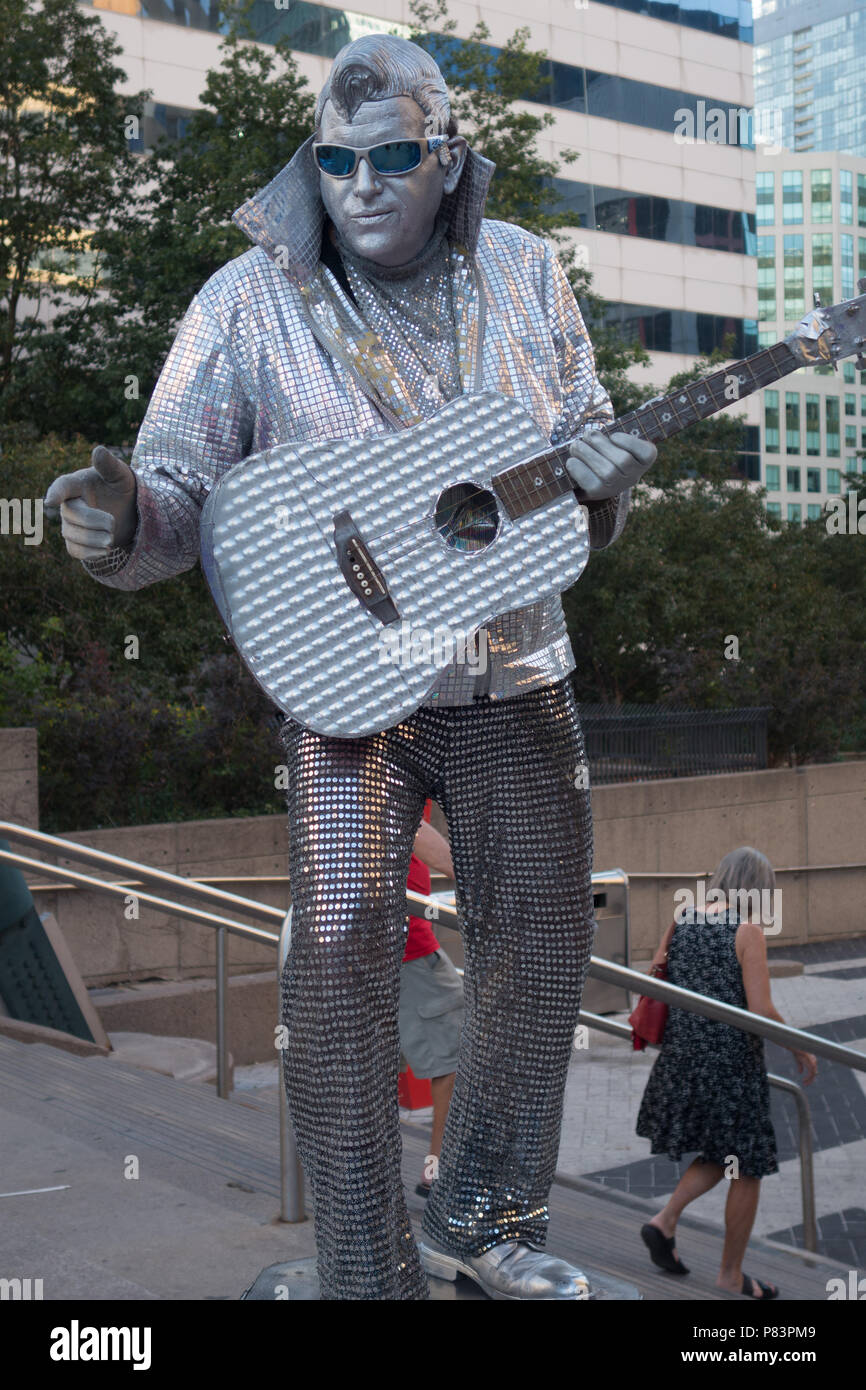 An Elvis impersonator street performer with his skin painted silver ...