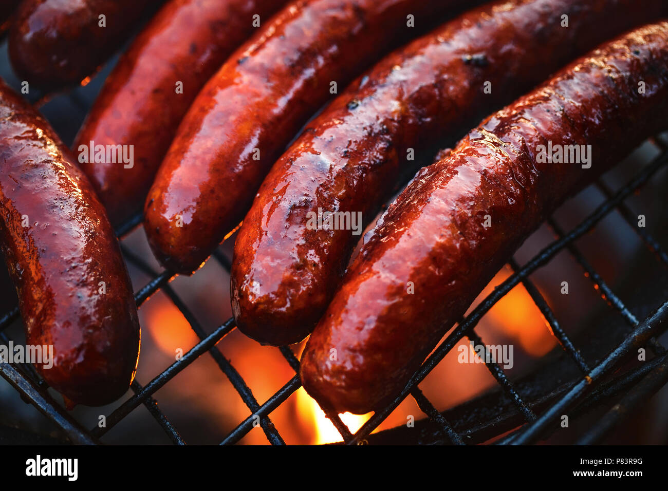 Grilled sausages on the grill with flames close up. BBQ background ...