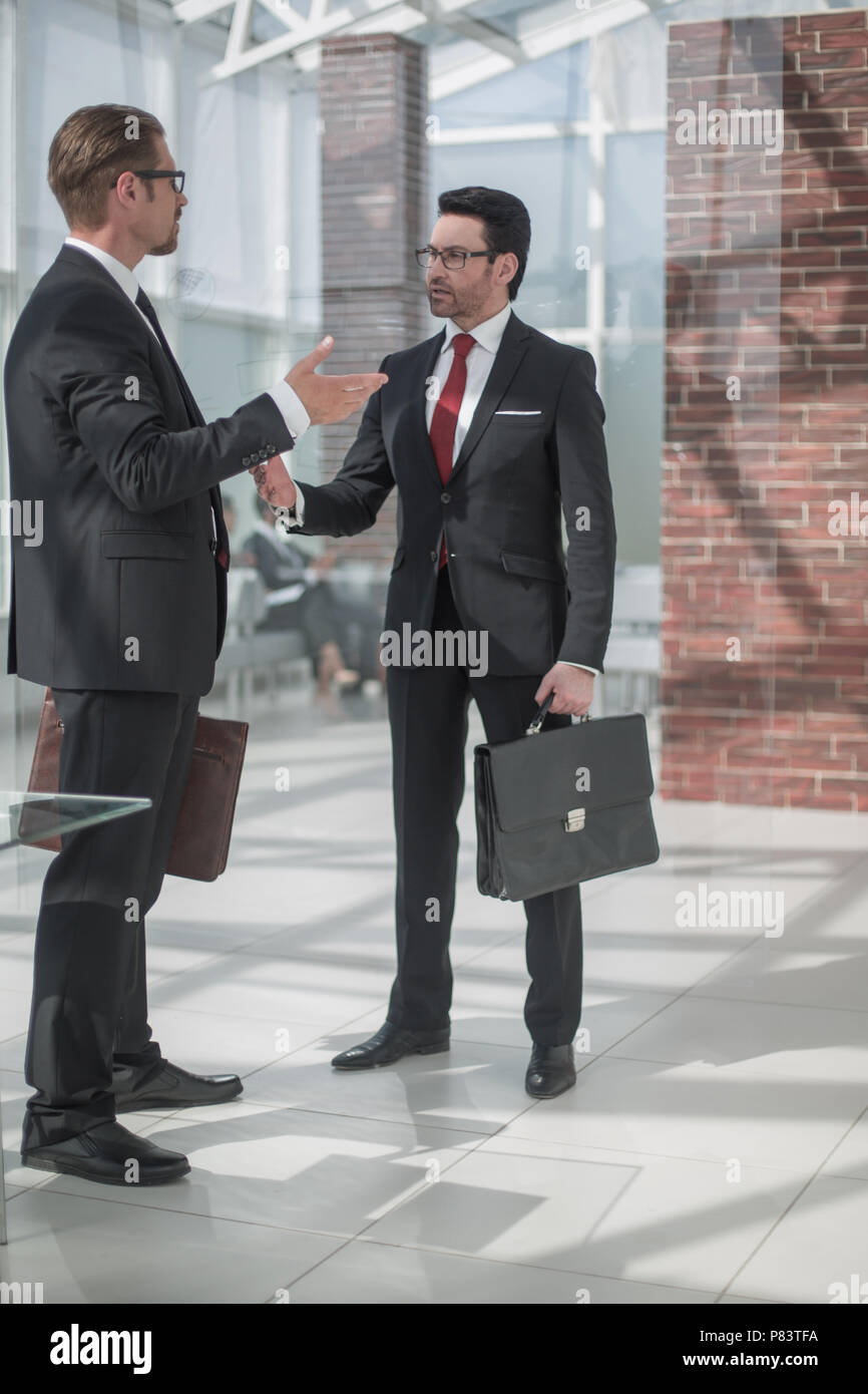 two businessmen talking in the office hall Stock Photo - Alamy