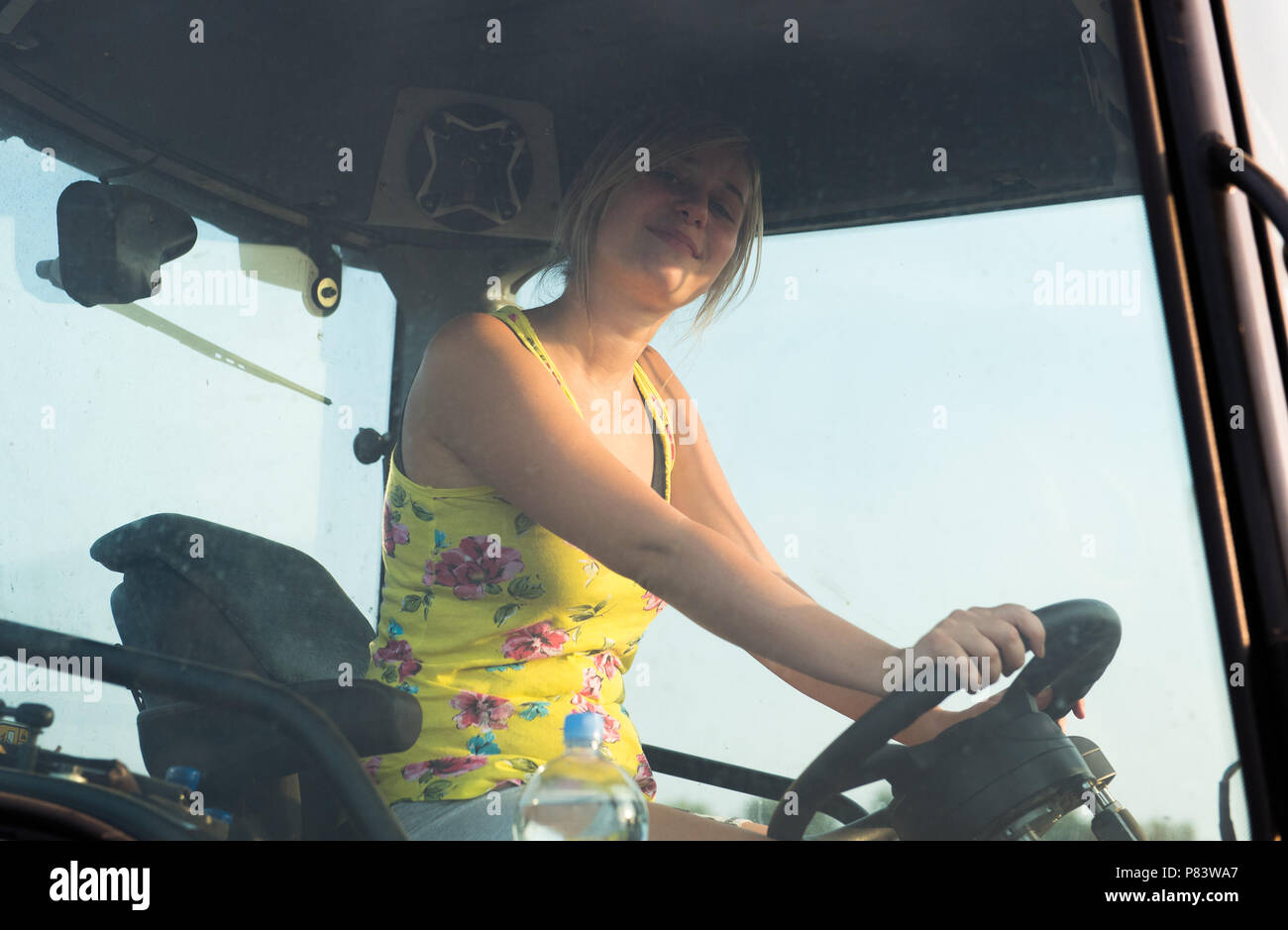 Beautiful, young farmer girl is driving tractor at field Stock Photo ...