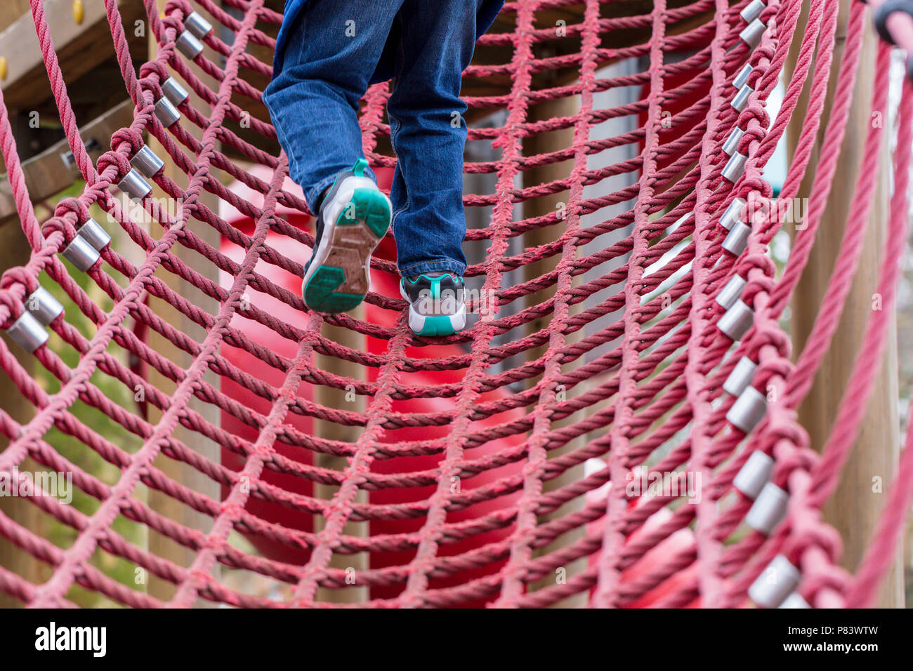 Young child playing on a rope climbing frame in Battersea Park, London ...