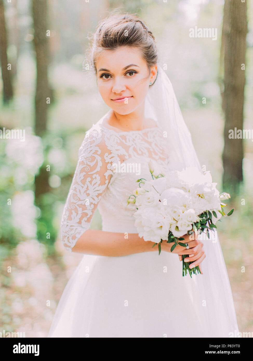 Outdoor portrait of the charming bride holding the wedding bouquet of ...