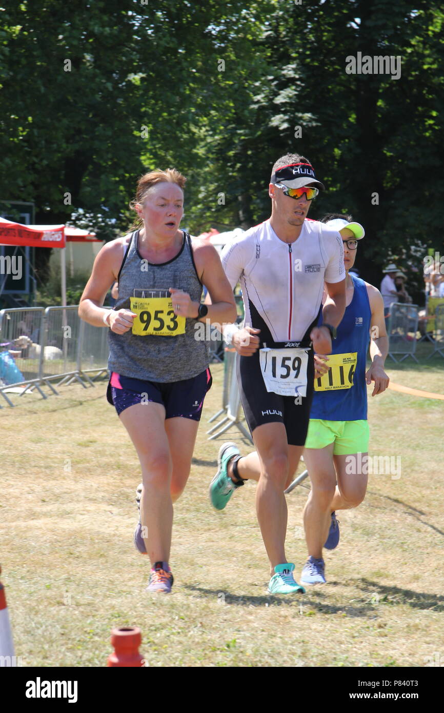 three runners, male and female, running across grass during a race ...