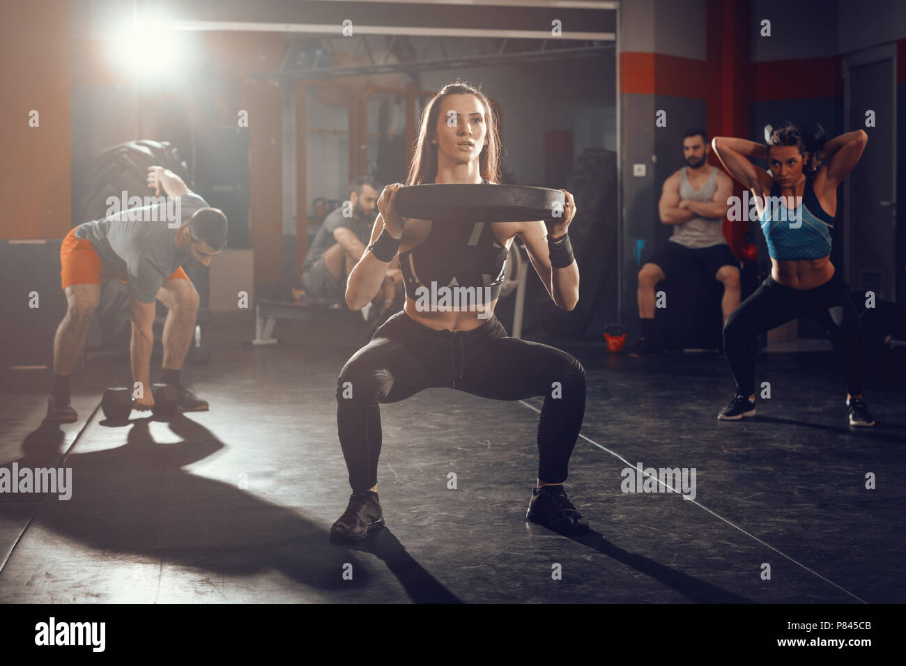 Young muscular cute woman doing hard exercise with heavy plate at the ...