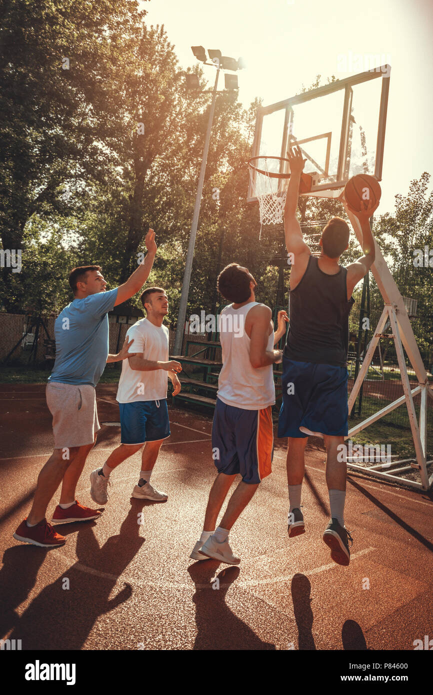 Four basketball players have a training outdoor. They are playing and ...