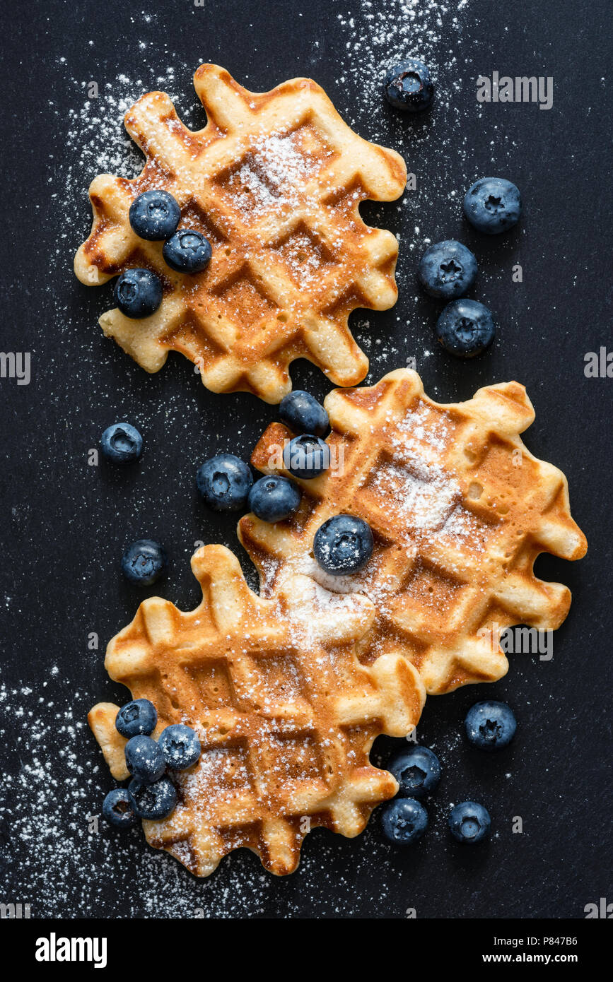 Waffles with blueberries and sugar on slate, top view, vertical ...