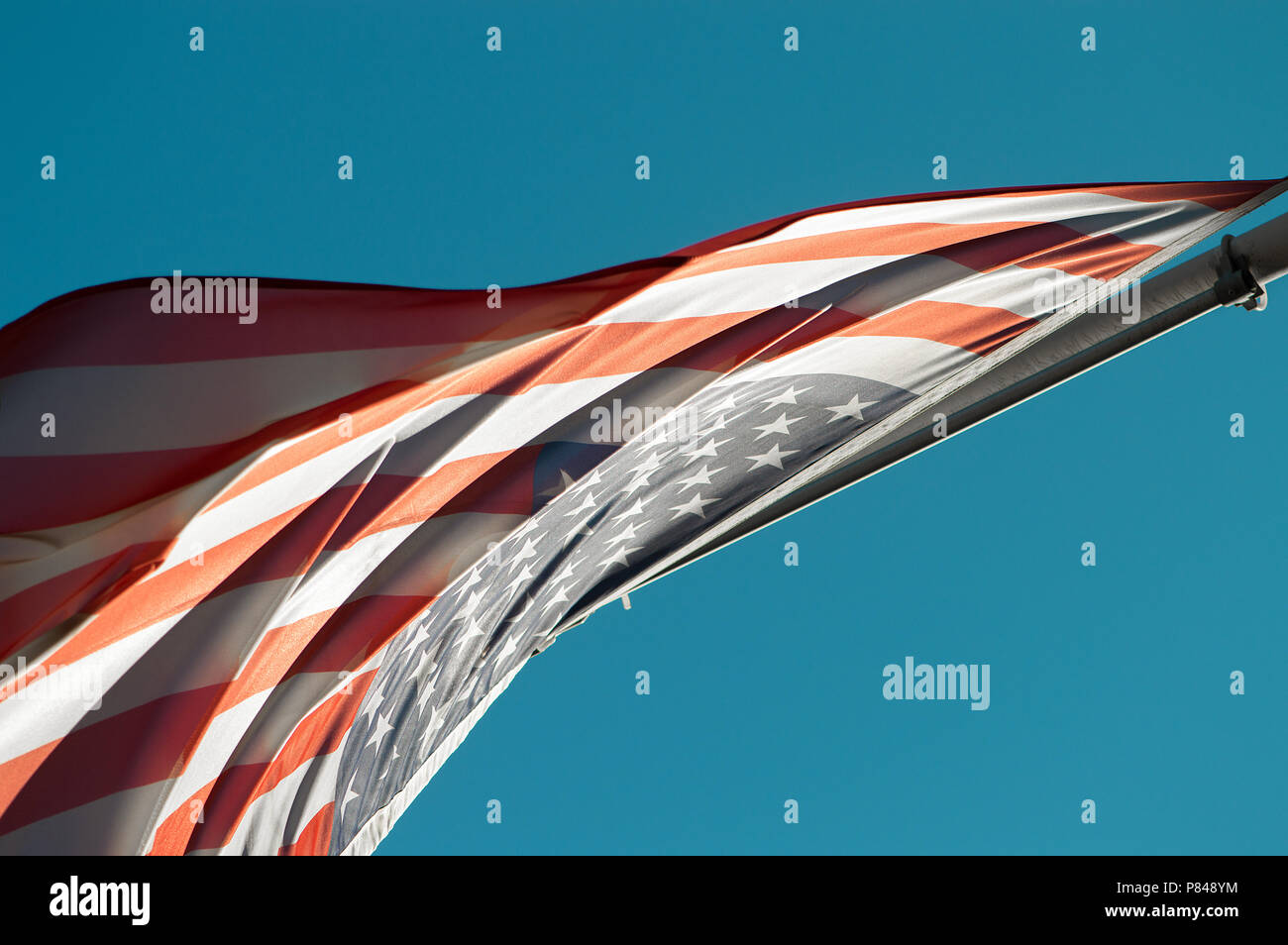 American flag with stars and stripes flying in the wind on blue sky ...