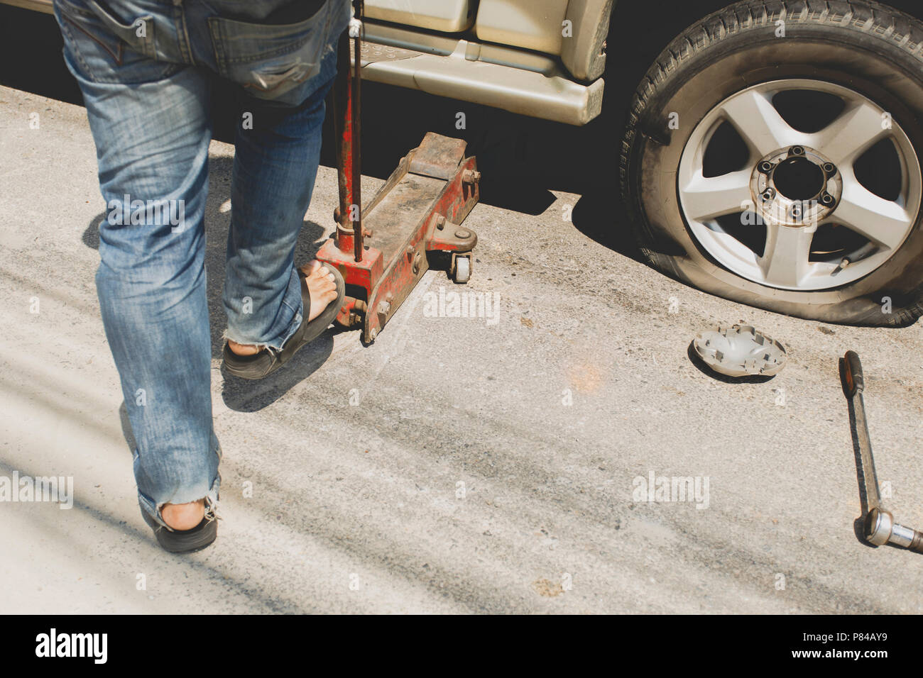 A man changing the wheel at the side of the road Stock Photo - Alamy