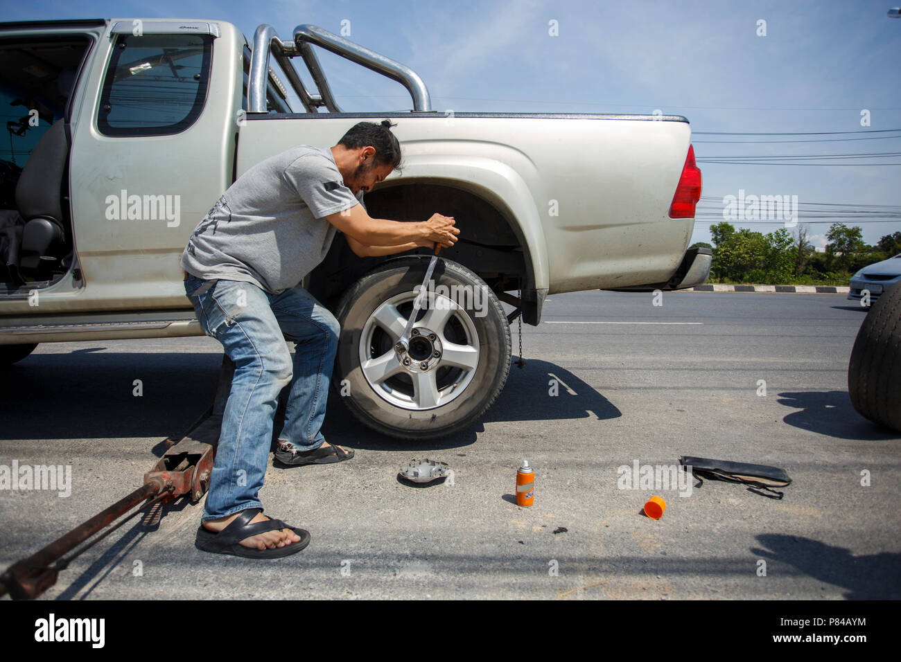 A man changing the wheel at the side of the road Stock Photo - Alamy