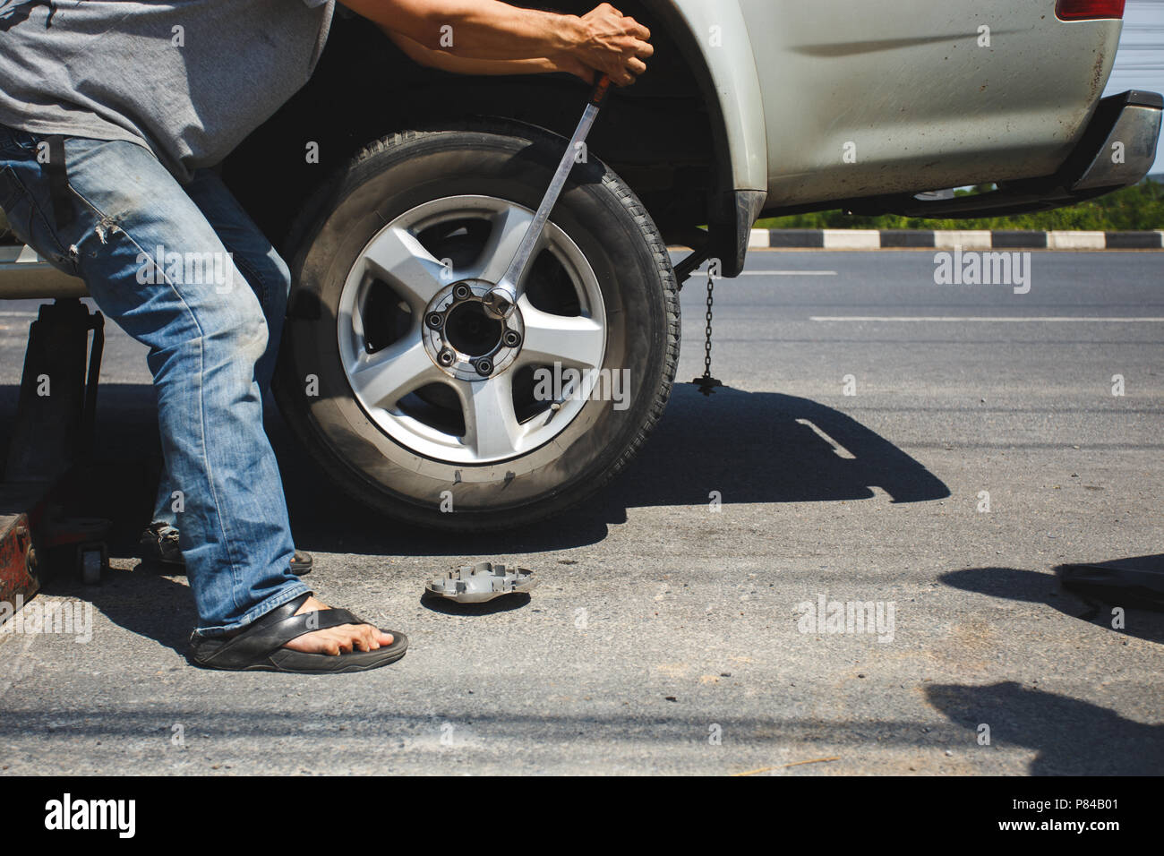 A man changing the wheel at the side of the road Stock Photo - Alamy