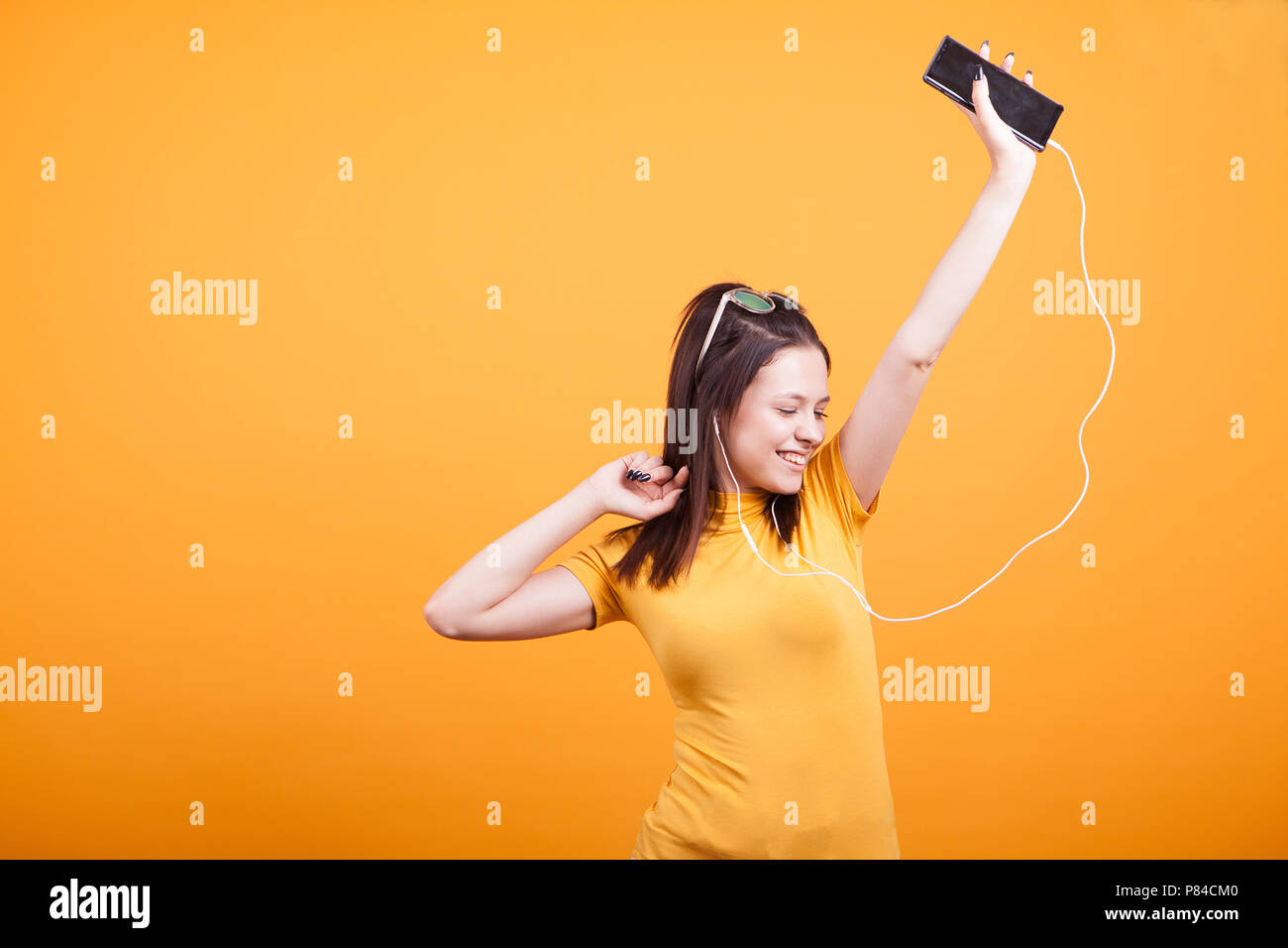 Cute girl dancing while listening music on her phone in studio on ...