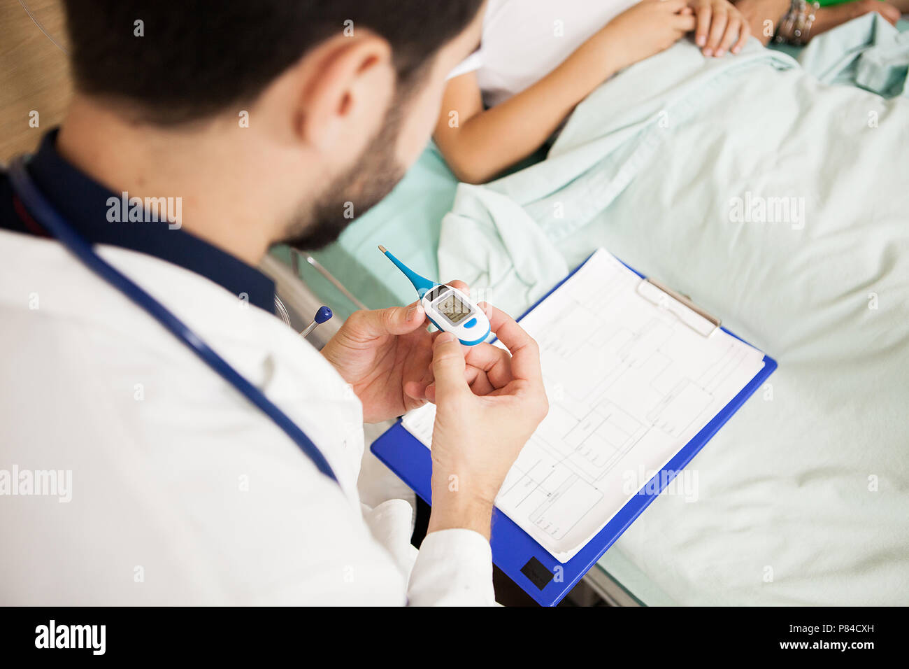 Doctor taking body temperature of her patient in hospital room Stock ...
