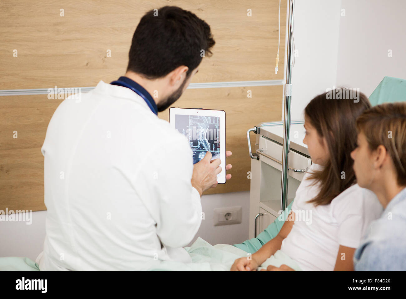 Doctor showing the xray on his tablet pc to her patient girl Stock ...