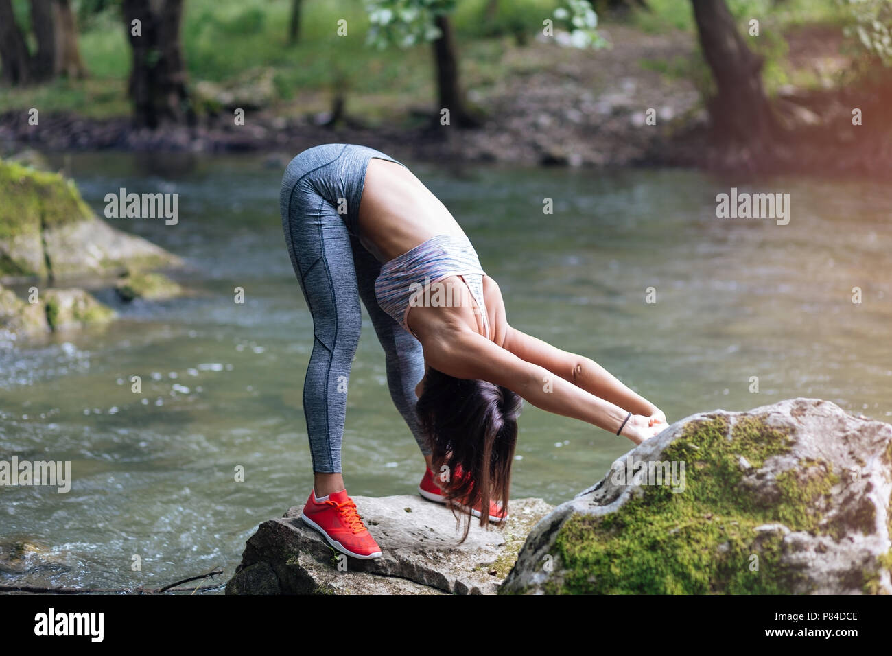 Pretty girl stretching on rocks Stock Photo - Alamy