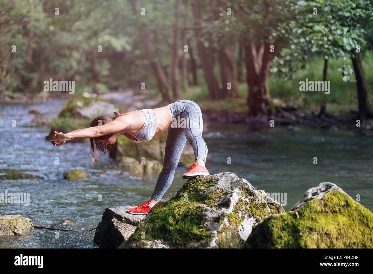 Pretty girl stretching on rocks Stock Photo - Alamy