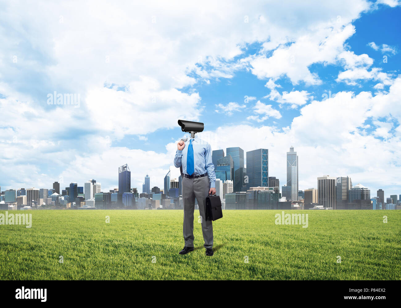 Camera headed man standing on green grass against modern cityscape ...