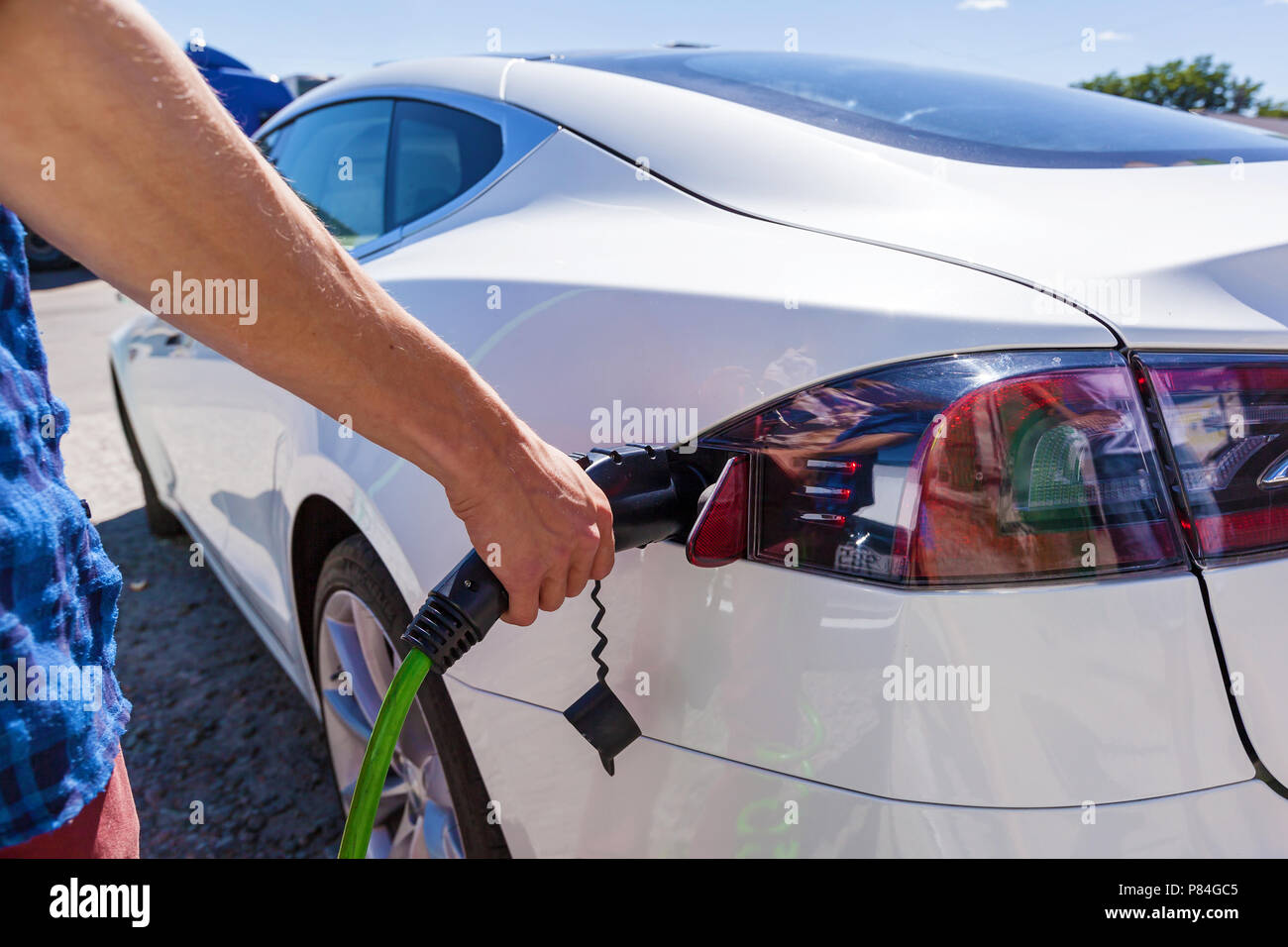 Man inserts the charger into an electric vehicle. Electric vehicle ...