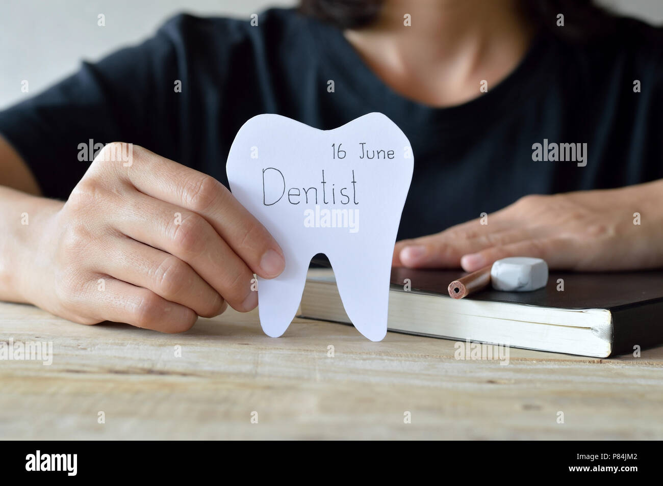 woman hold paper cut tooth shape write the word that dentist and date ...