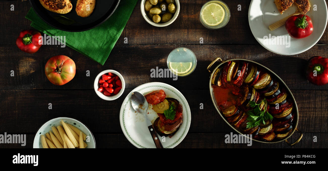 Different vegetarian food on wooden table. Ratatouille, chickpeas ...