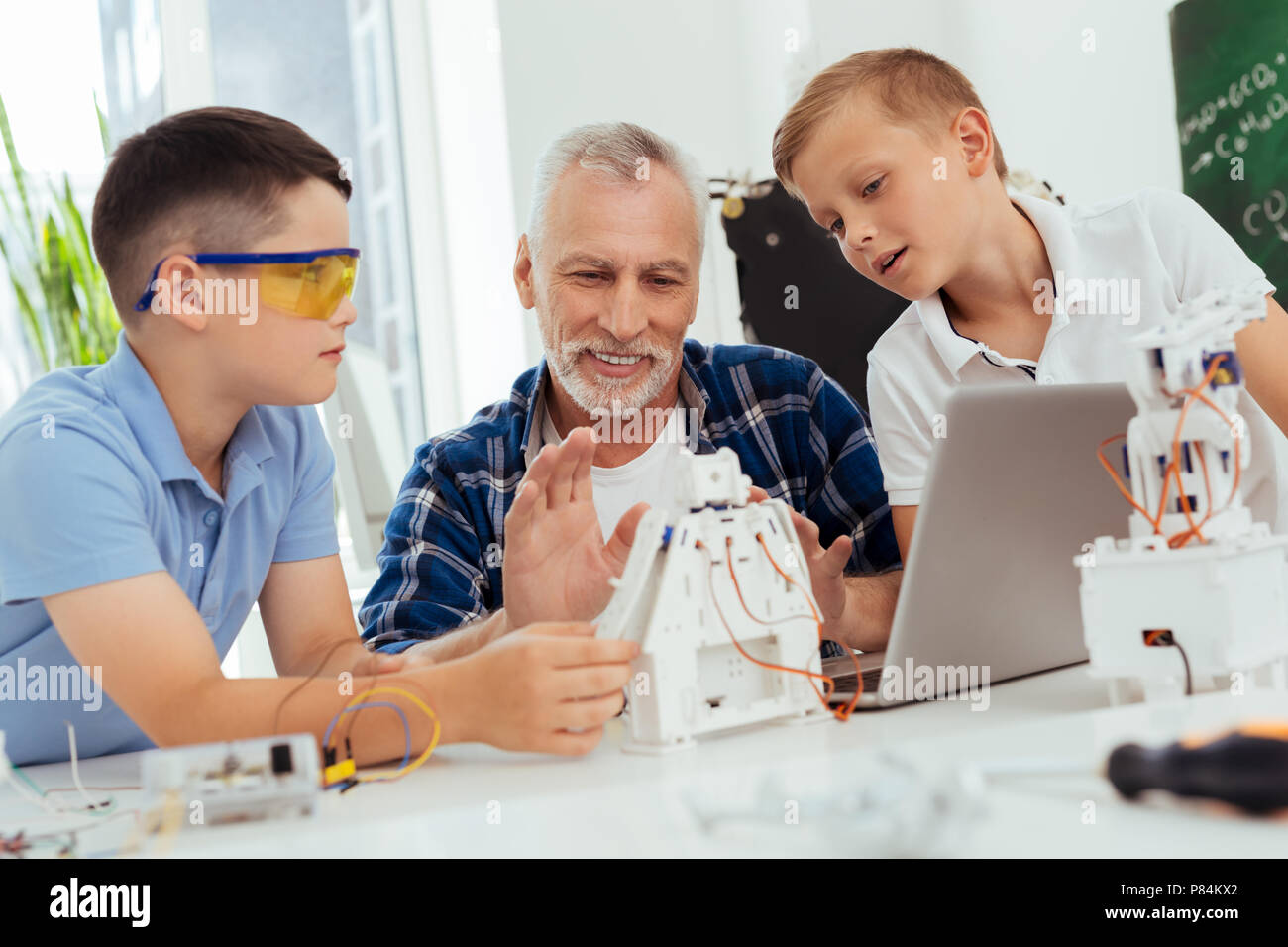 Delighted intelligent boys looking at the robot Stock Photo - Alamy