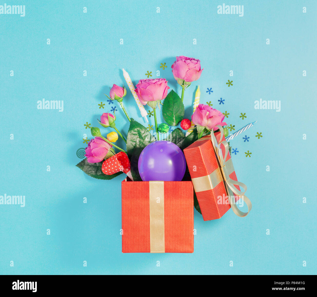 Small red gift box with roses, balloon, confetti and candles, top view ...