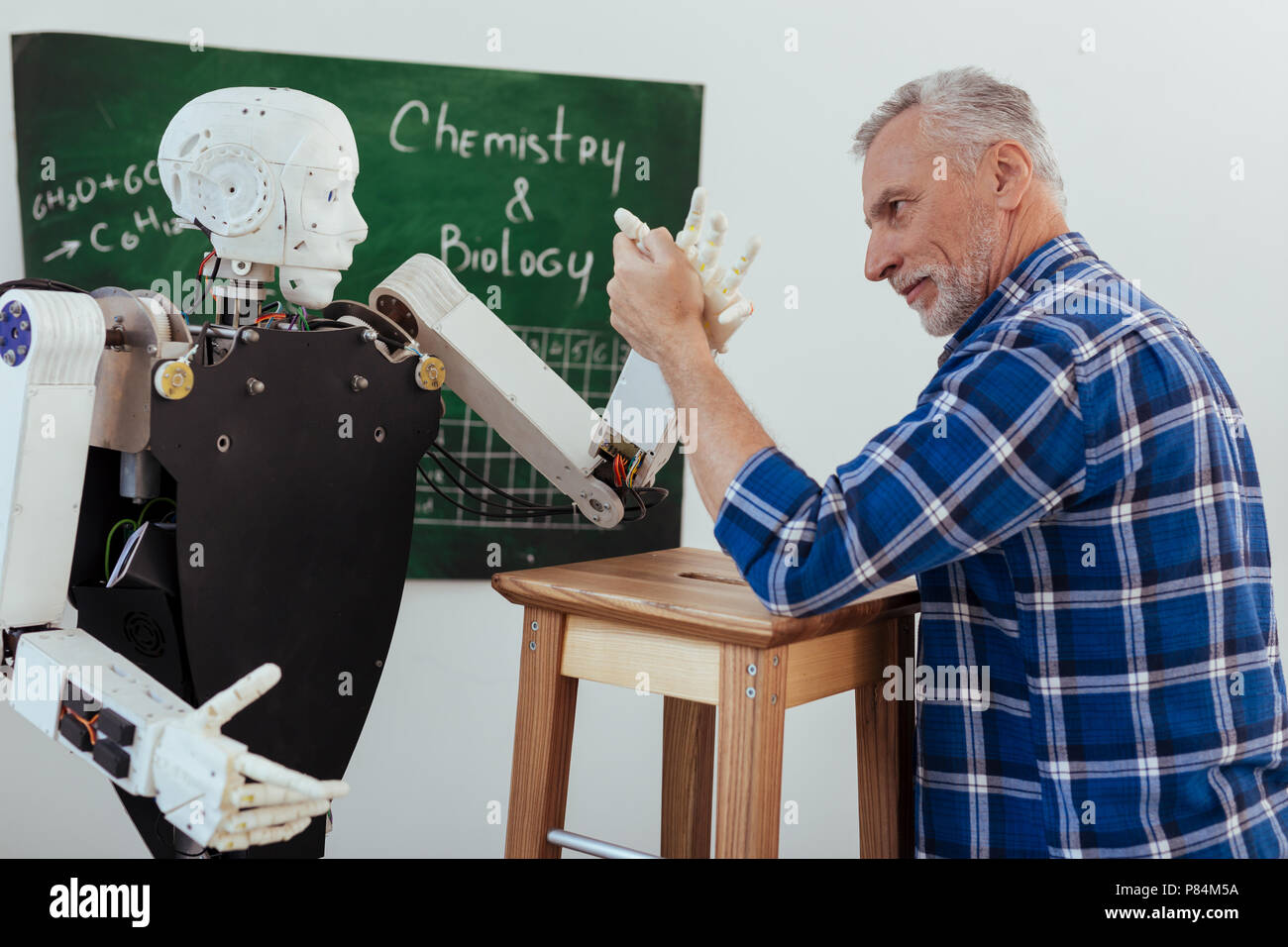 Strong aged man looking at the robot Stock Photo - Alamy