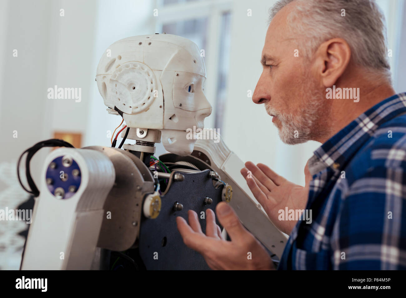 Serious smart engineer looking at the robot Stock Photo - Alamy