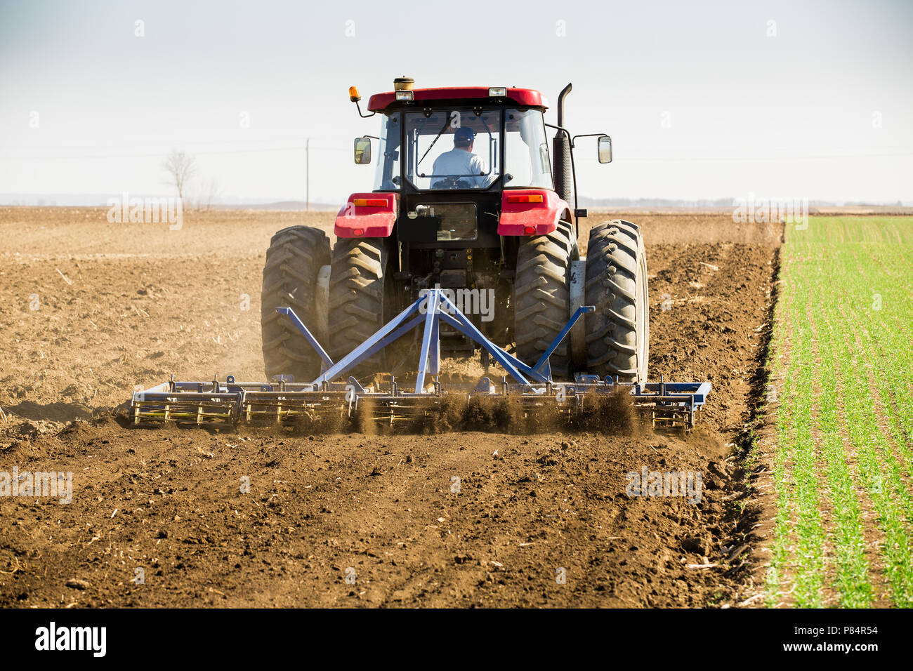 Farmer in tractor preparing land with seedbed cultivator as part of pre ...