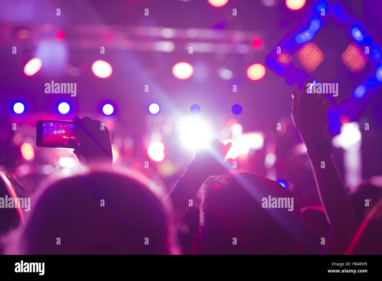 Audience with hands raised at a music festival and lights streaming ...