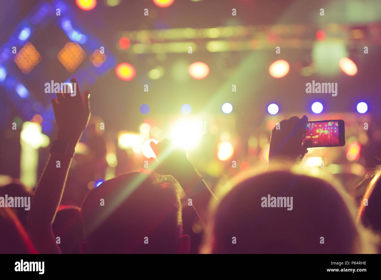 Audience with hands raised at a music festival and lights streaming ...