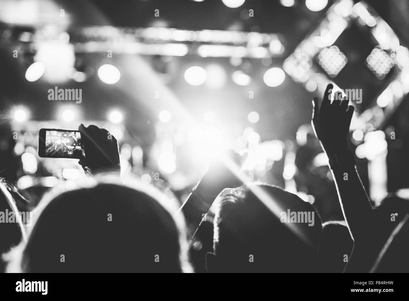 Audience with hands raised at a music festival and lights streaming ...