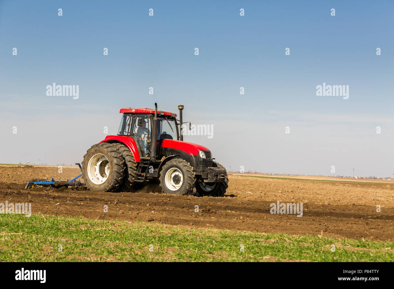 Tractor cultivating field at spring Stock Photo - Alamy