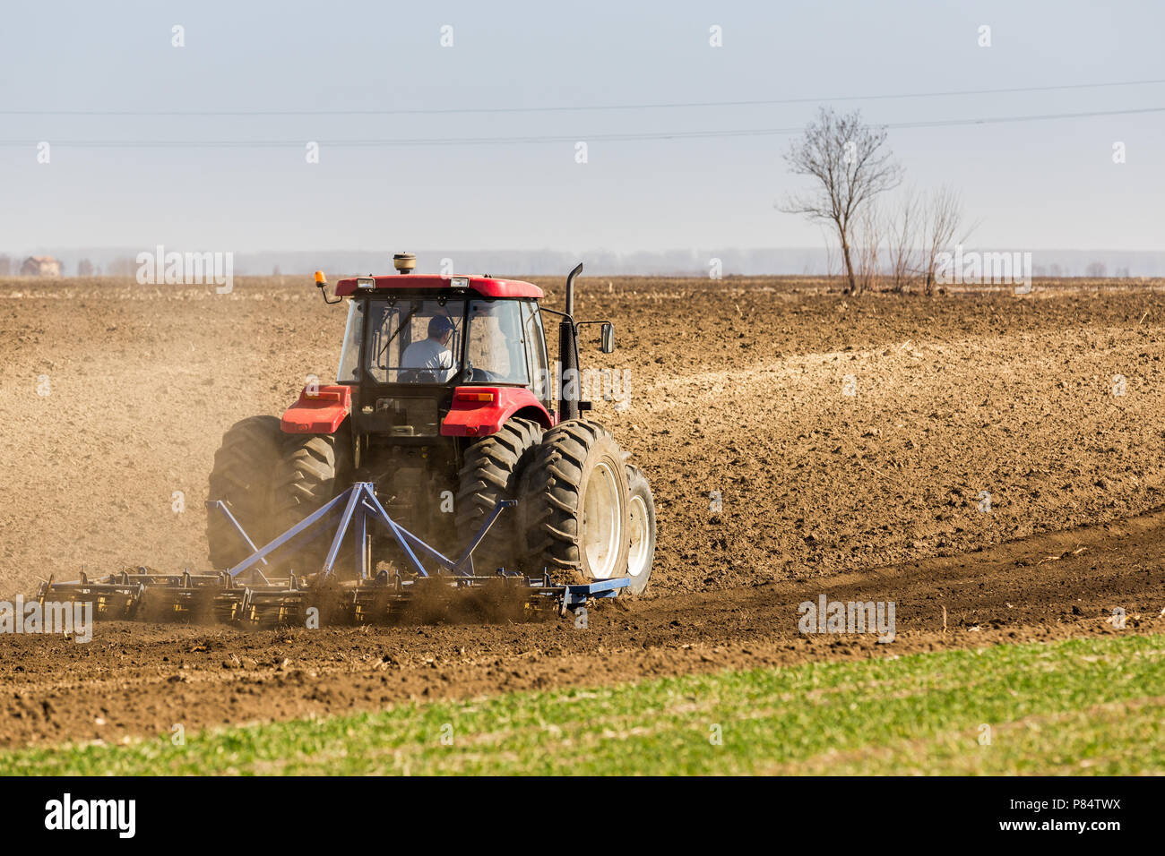 Tractor cultivating field at spring Stock Photo - Alamy