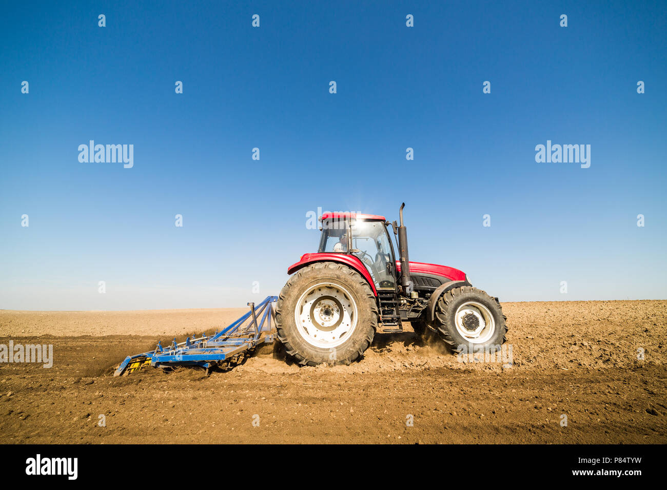 Tractor cultivating field at spring Stock Photo - Alamy