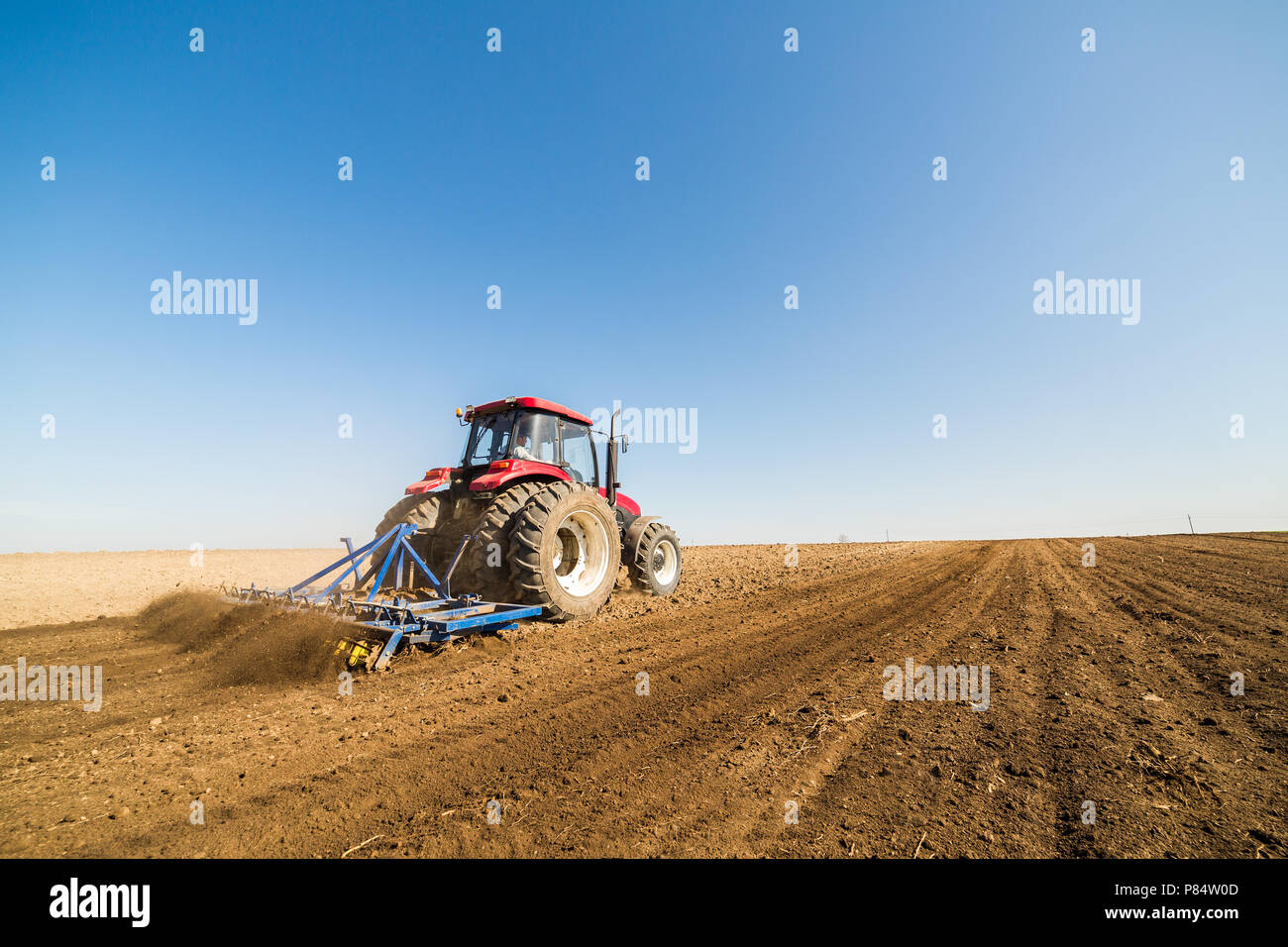 Tractor cultivating field at spring Stock Photo - Alamy