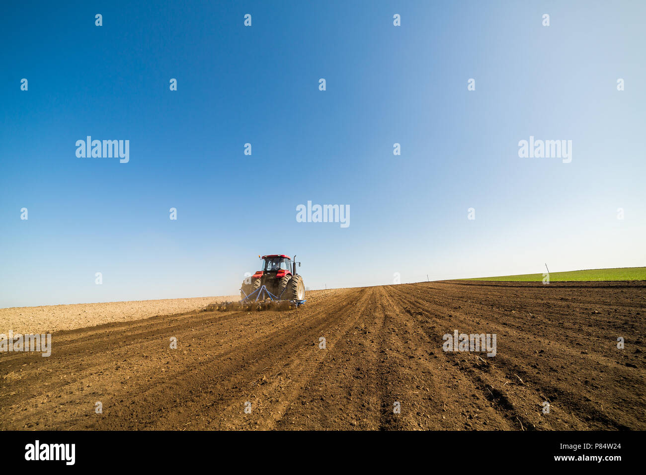 Tractor cultivating field at spring Stock Photo - Alamy