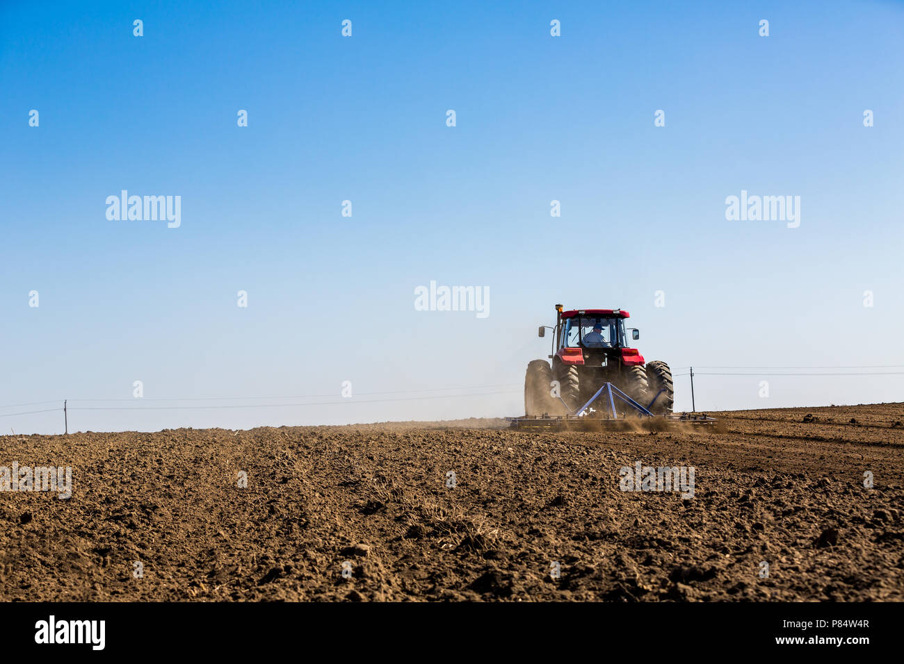 Tractor cultivating field at spring Stock Photo - Alamy