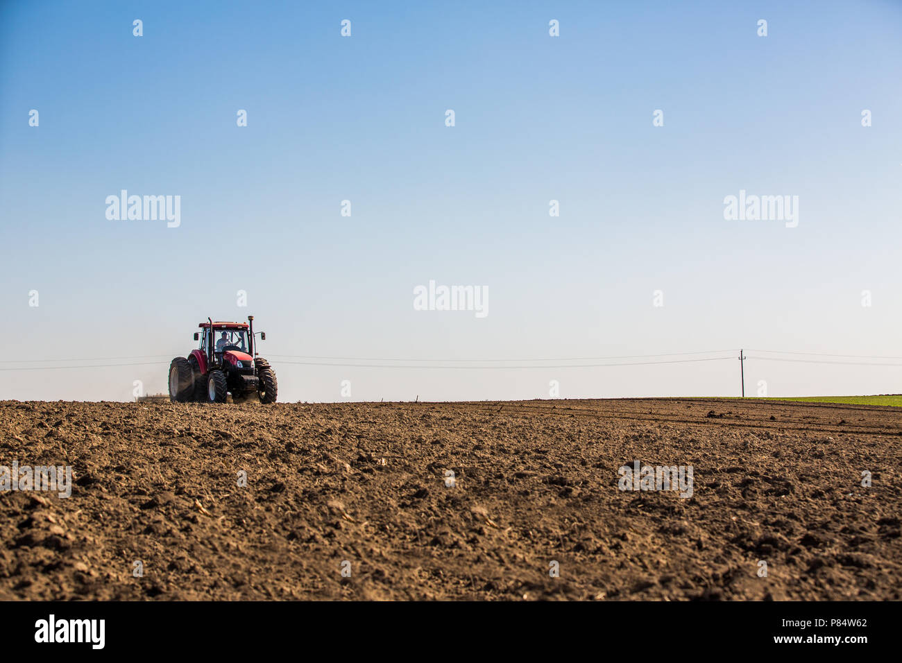 Tractor cultivating field at spring Stock Photo - Alamy