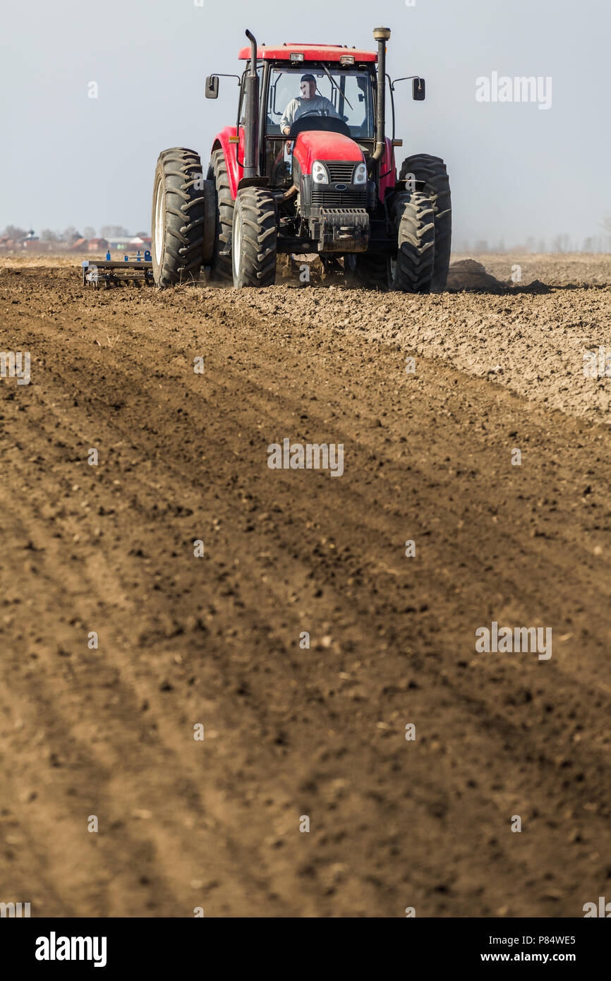 Tractor cultivating field at spring Stock Photo - Alamy