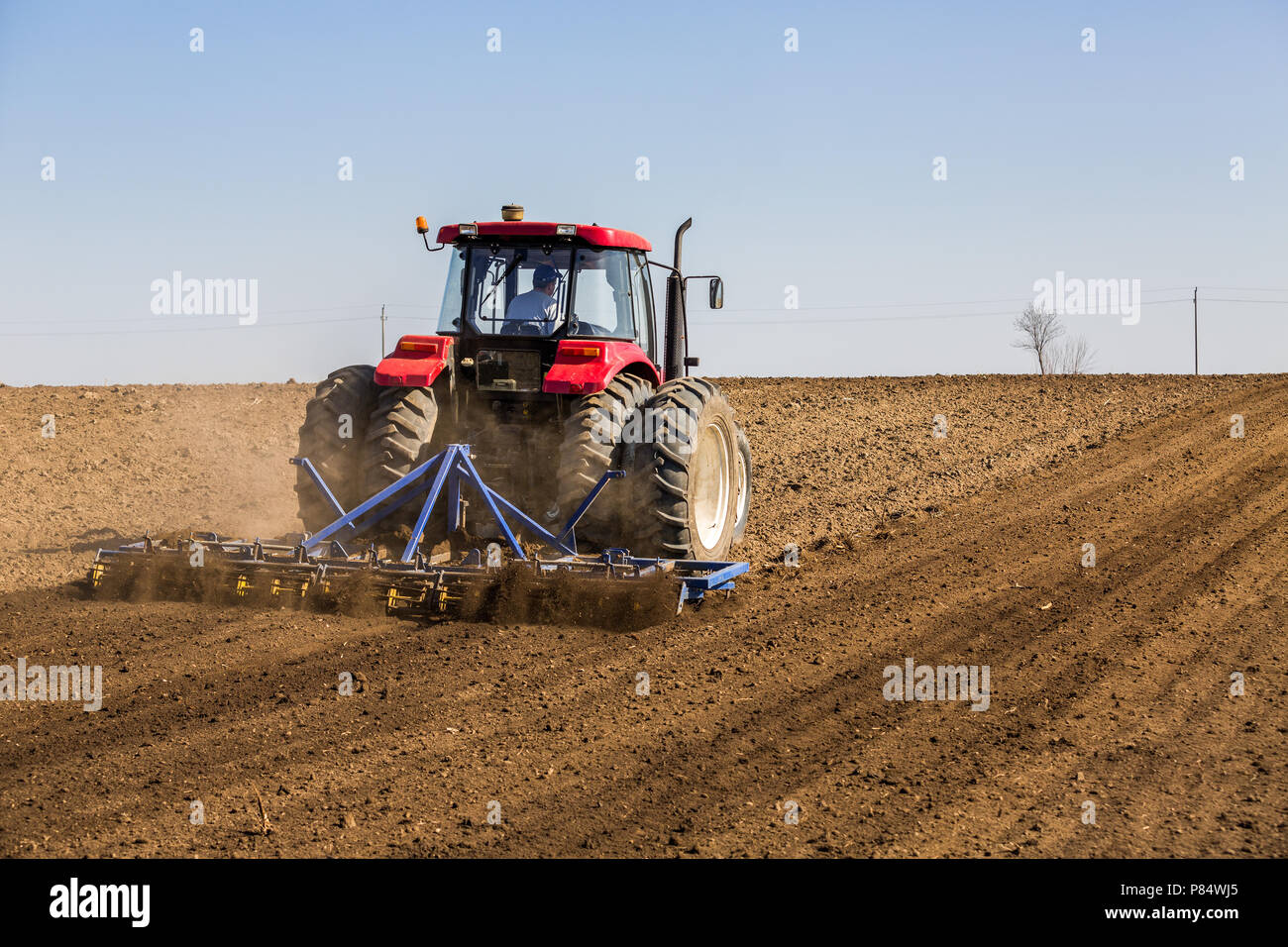 Tractor cultivating field at spring Stock Photo - Alamy